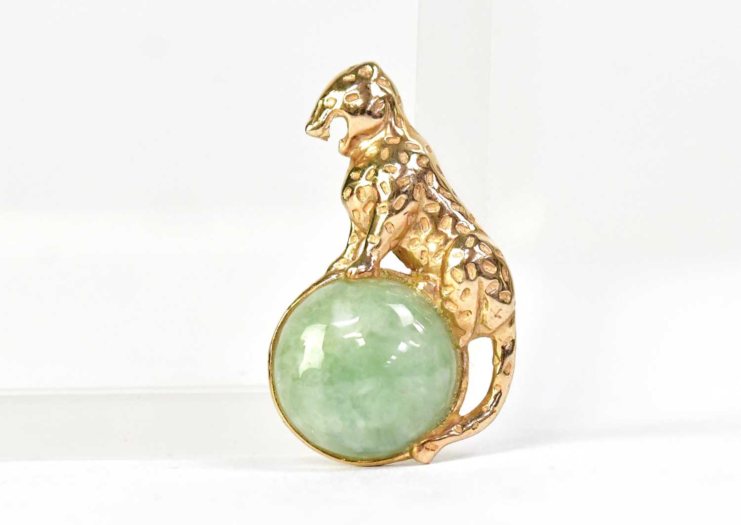 A 9ct yellow gold pendant in the form of a leopard balancing on a jade ...