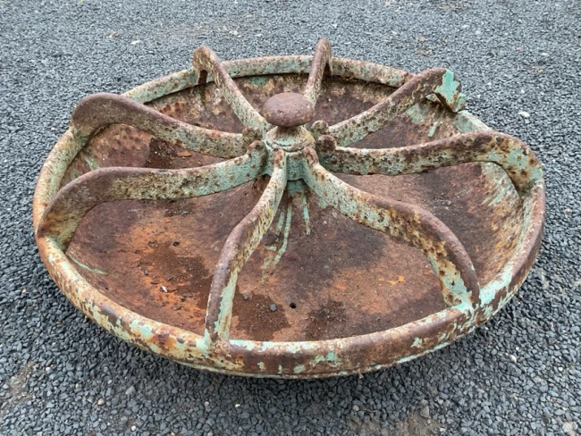 A circular cast iron trough feeder with eight divisions around central ...