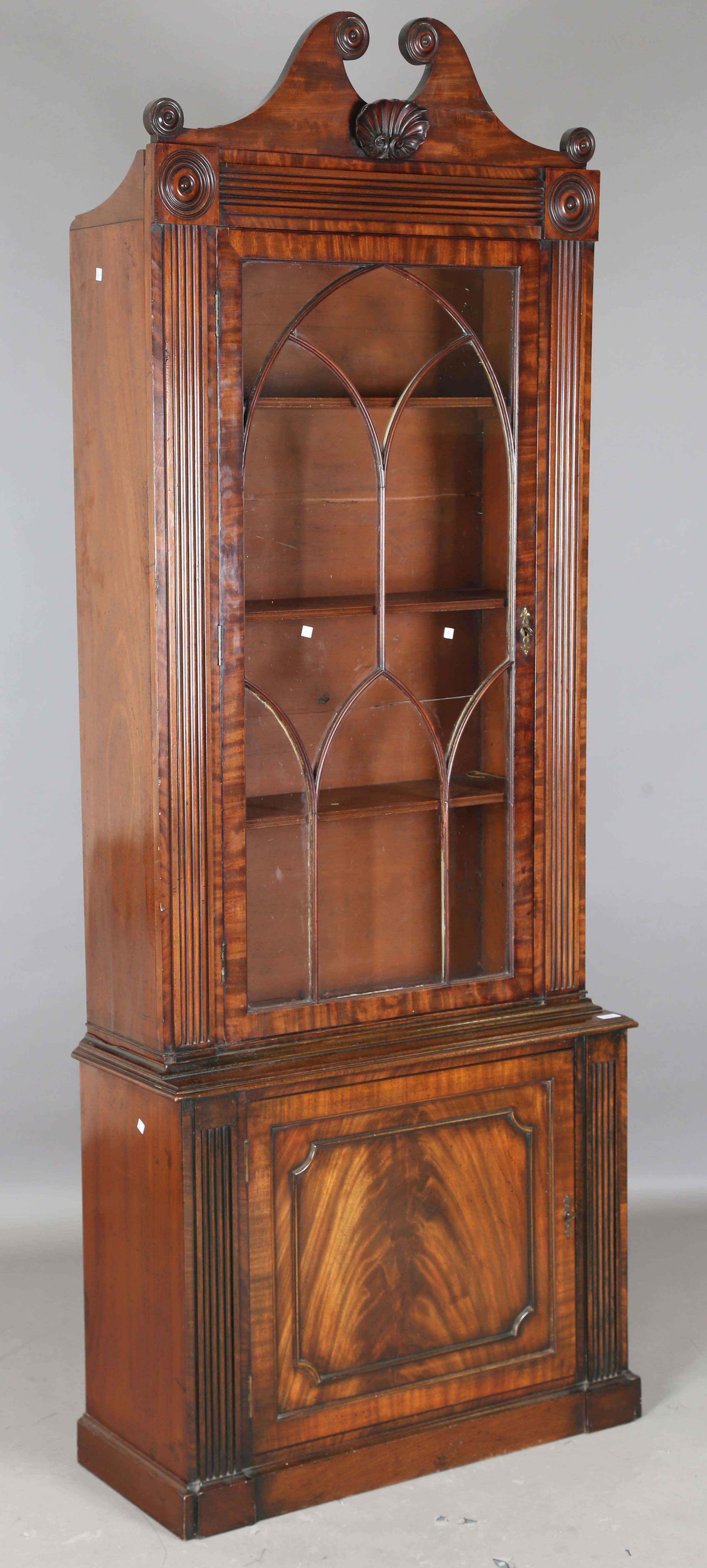 A 19th century mahogany narrow bookcase, the carved scroll and scallop ...