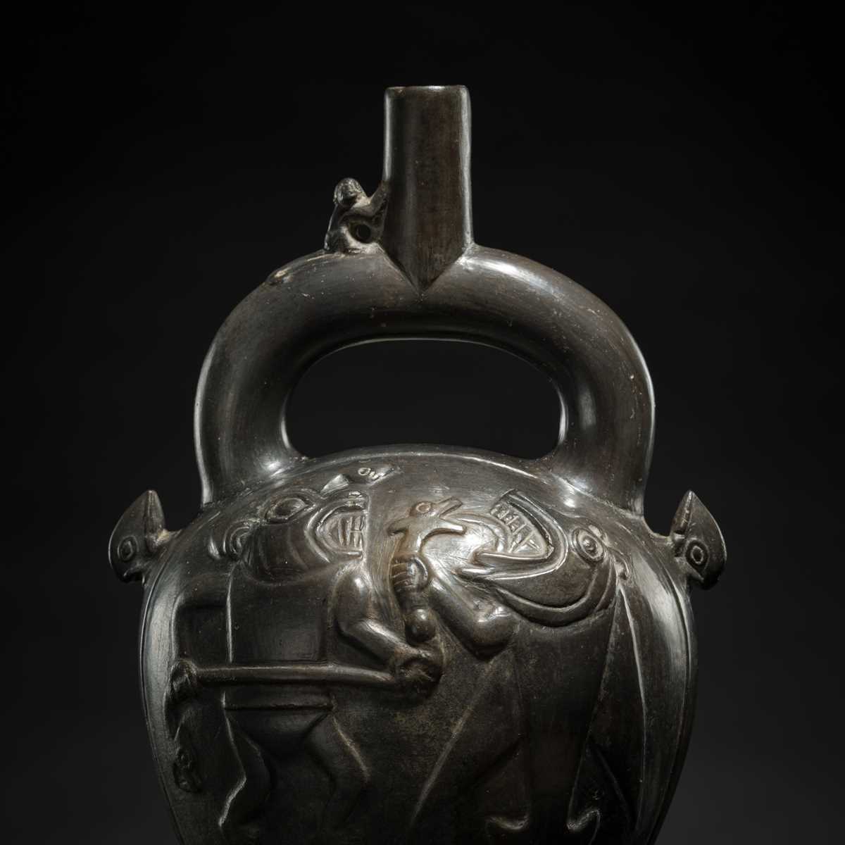 A CERAMIC STIRRUP-SPOUT VESSEL WITH TWO MYTHICAL CREATURES BATTLING ...